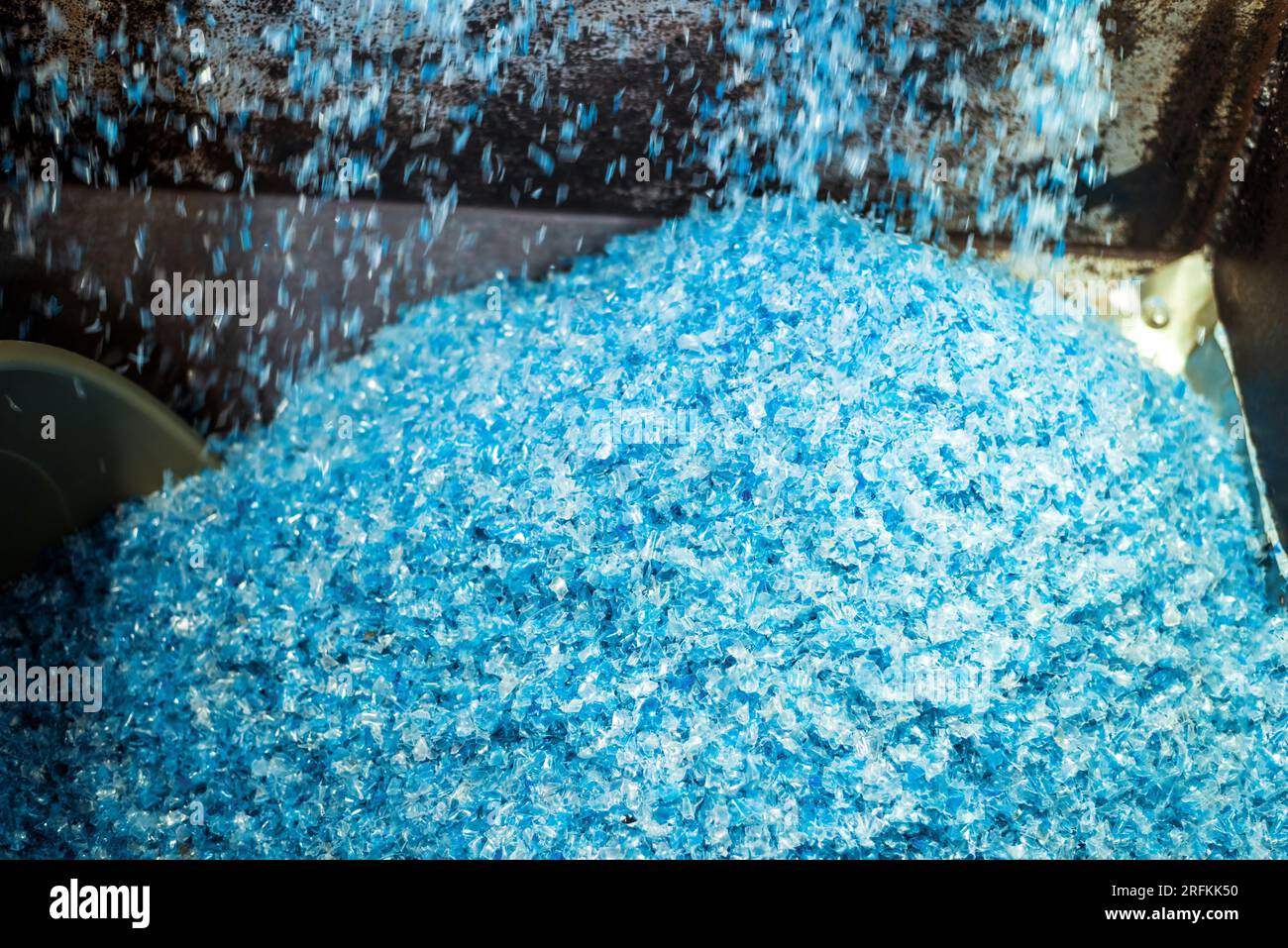 Close view of the blue shredded plastic garbage falling from a conveyor belt at waste recycling ...