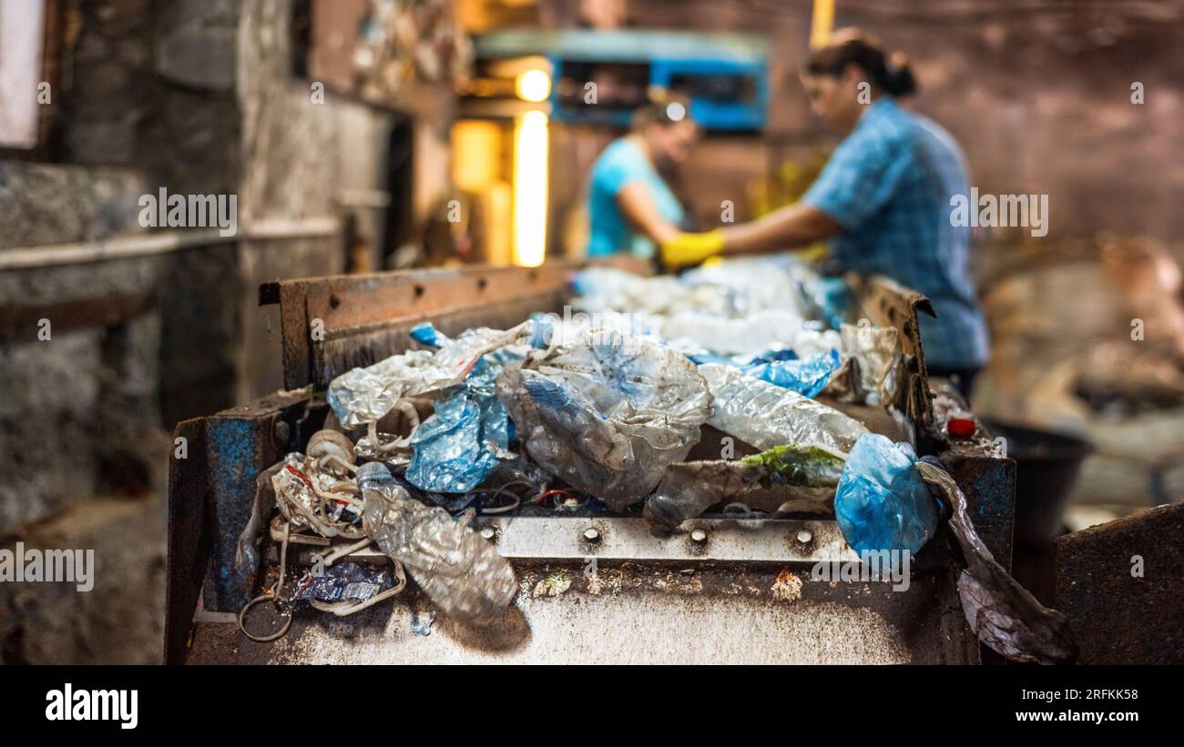 Plastic garbage on a conveyor belt at waste recycling factory. Workers on the background Stock ...