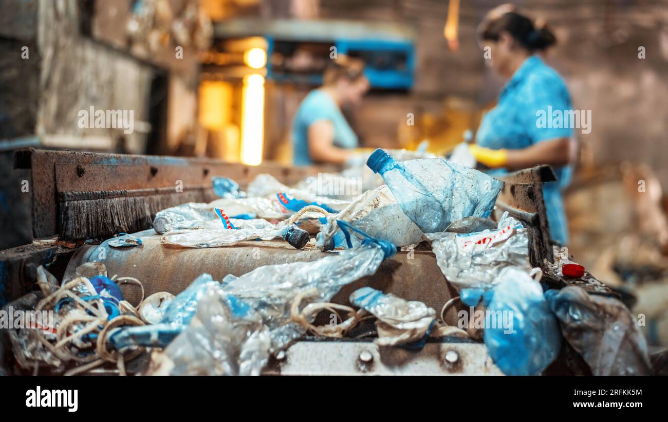 Plastic garbage on a conveyor belt at waste recycling factory. Workers on the background Stock ...