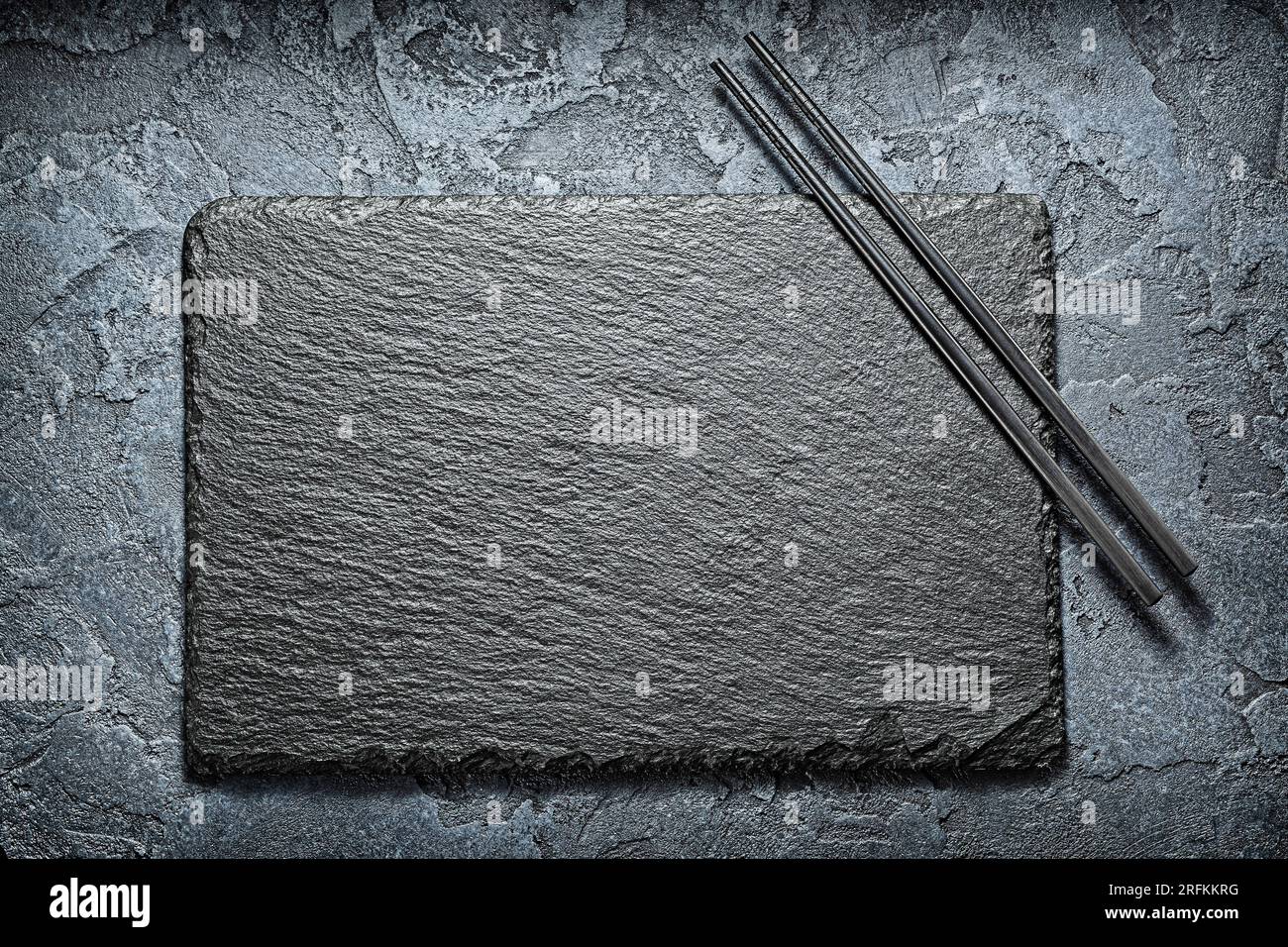 Black Choppingsticks On Stone Slate Plater Stock Photo - Alamy