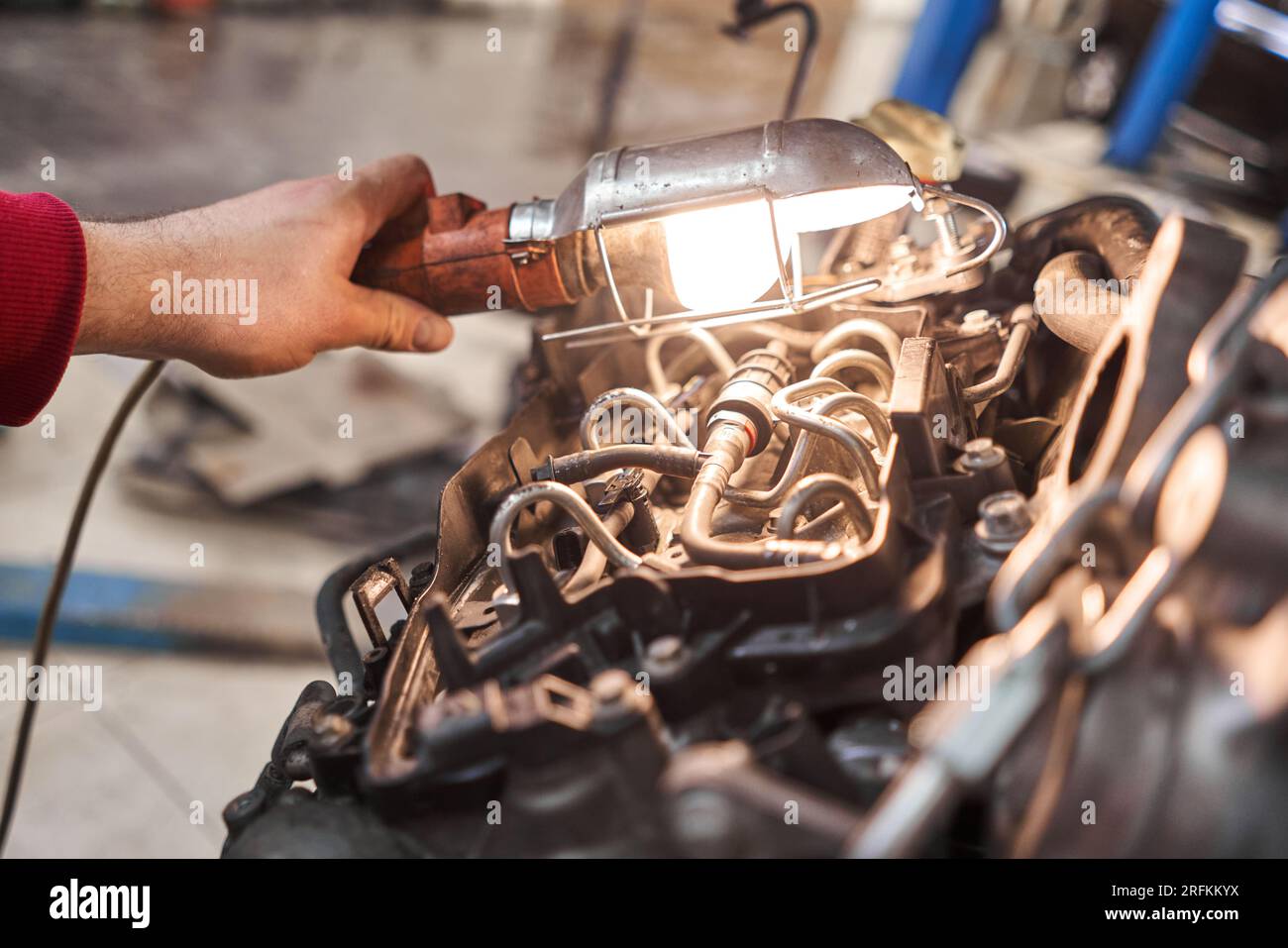 A car mechanic inspects the engine with a flashlight. Engine Block on a ...
