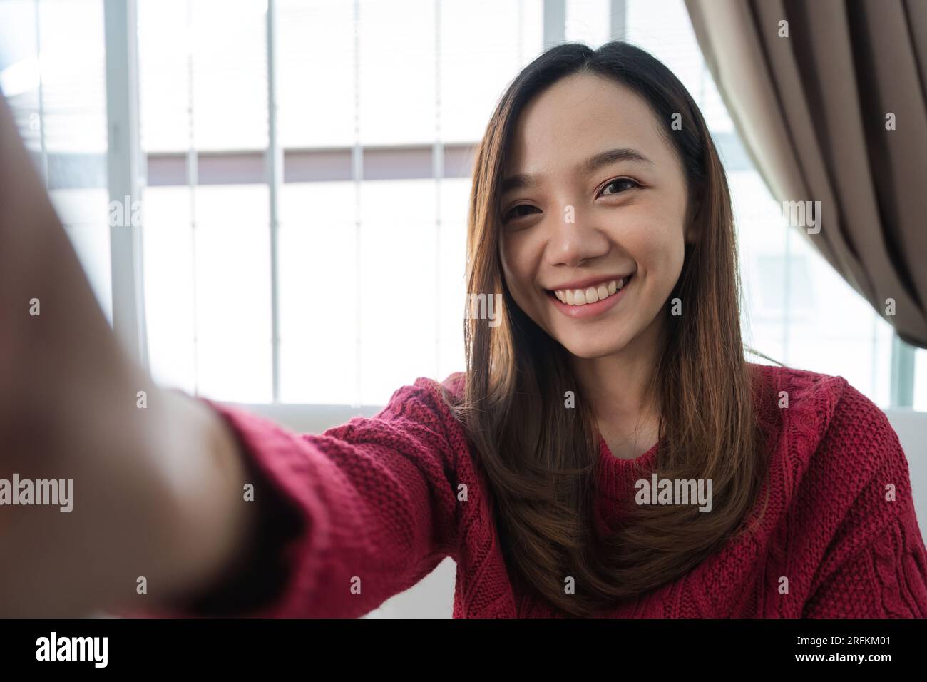 Pretty young asian female with big smile sitting at living room. She ...