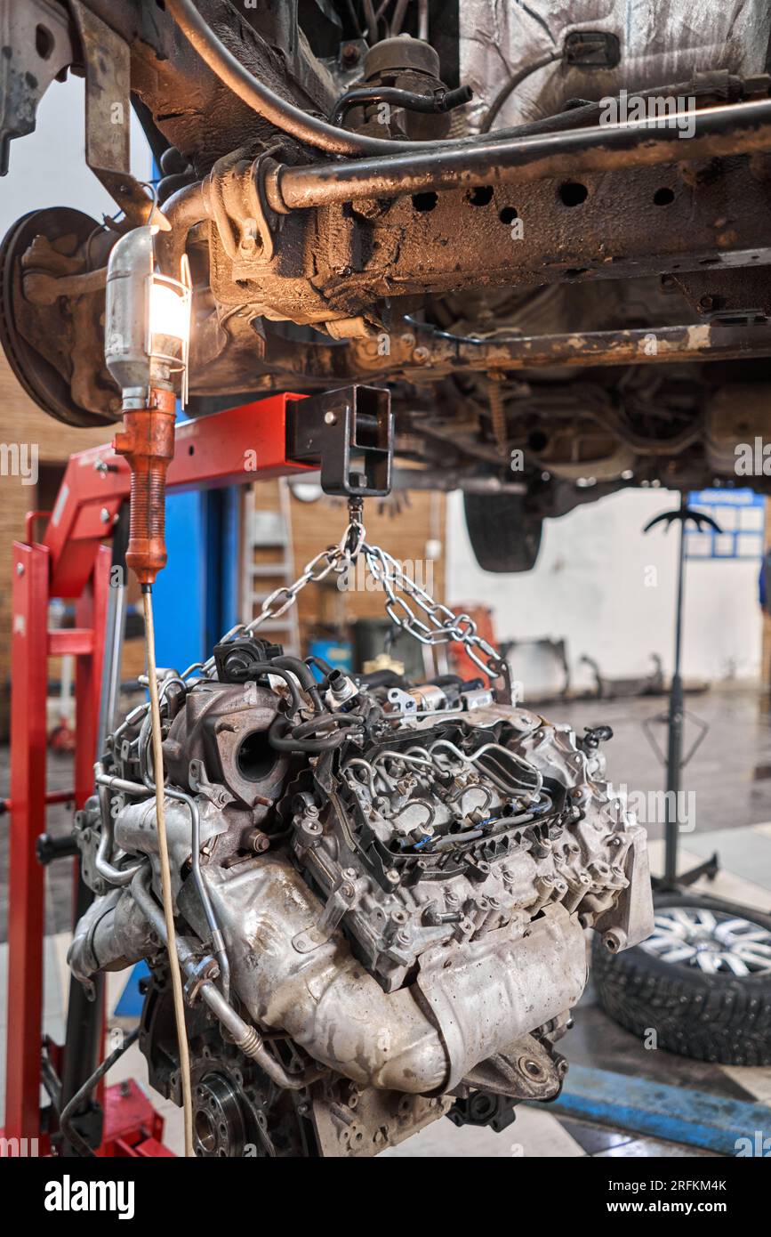 A car mechanic inspects the engine with a flashlight. Engine Block on a ...