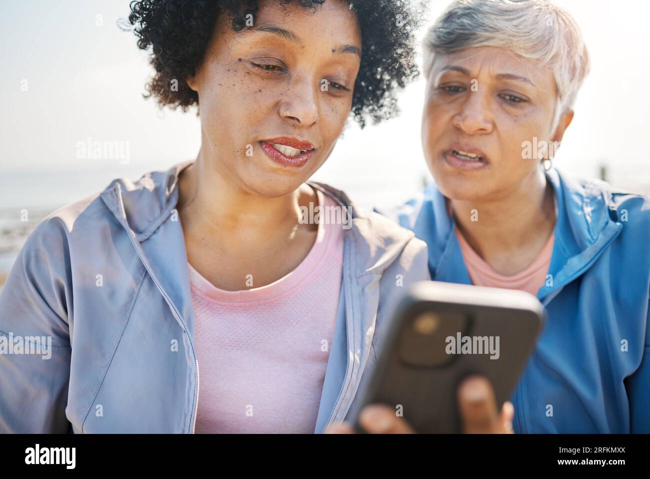 Phone, confused and senior friends on the beach together, browsing ...