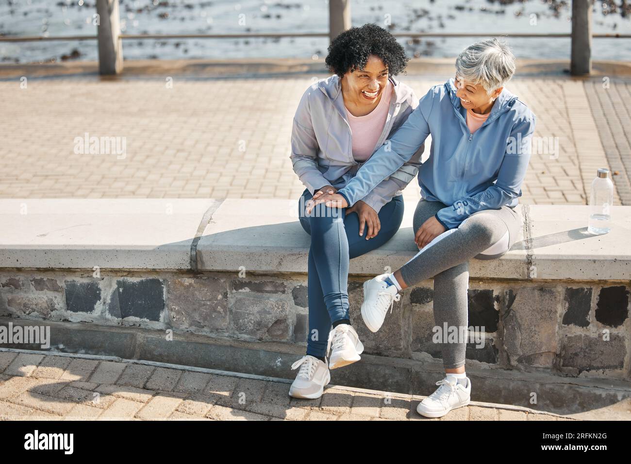 Senior women, bench sitting and beach with friends, training and laugh ...