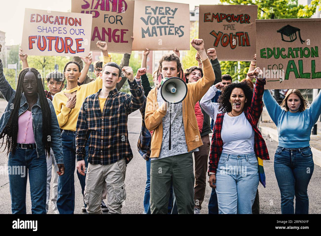 A diverse group of young students marching on the street, raising ...