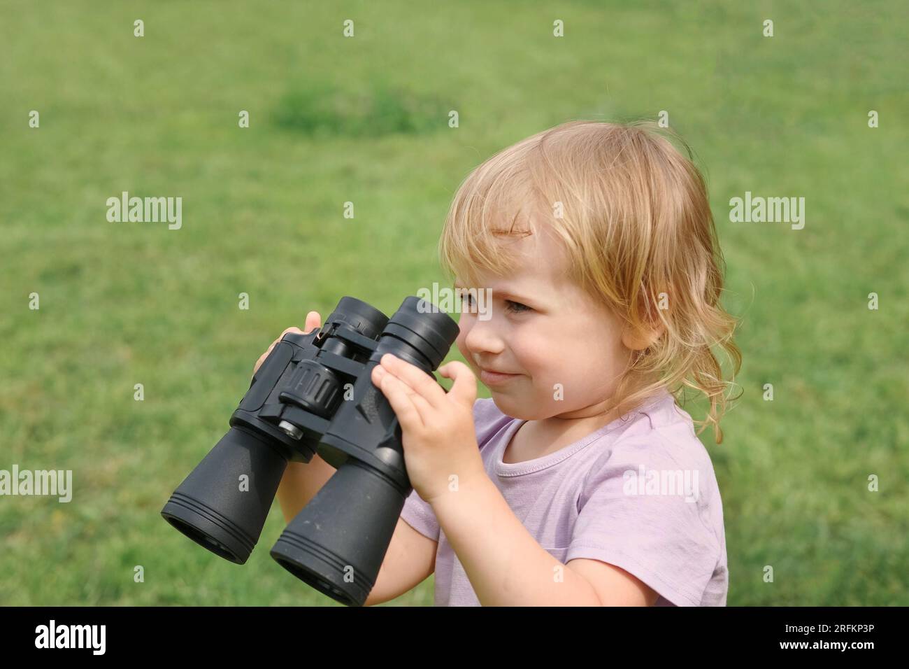 Little girl using binoculars in a forest. 2 years kid looking ahead ...