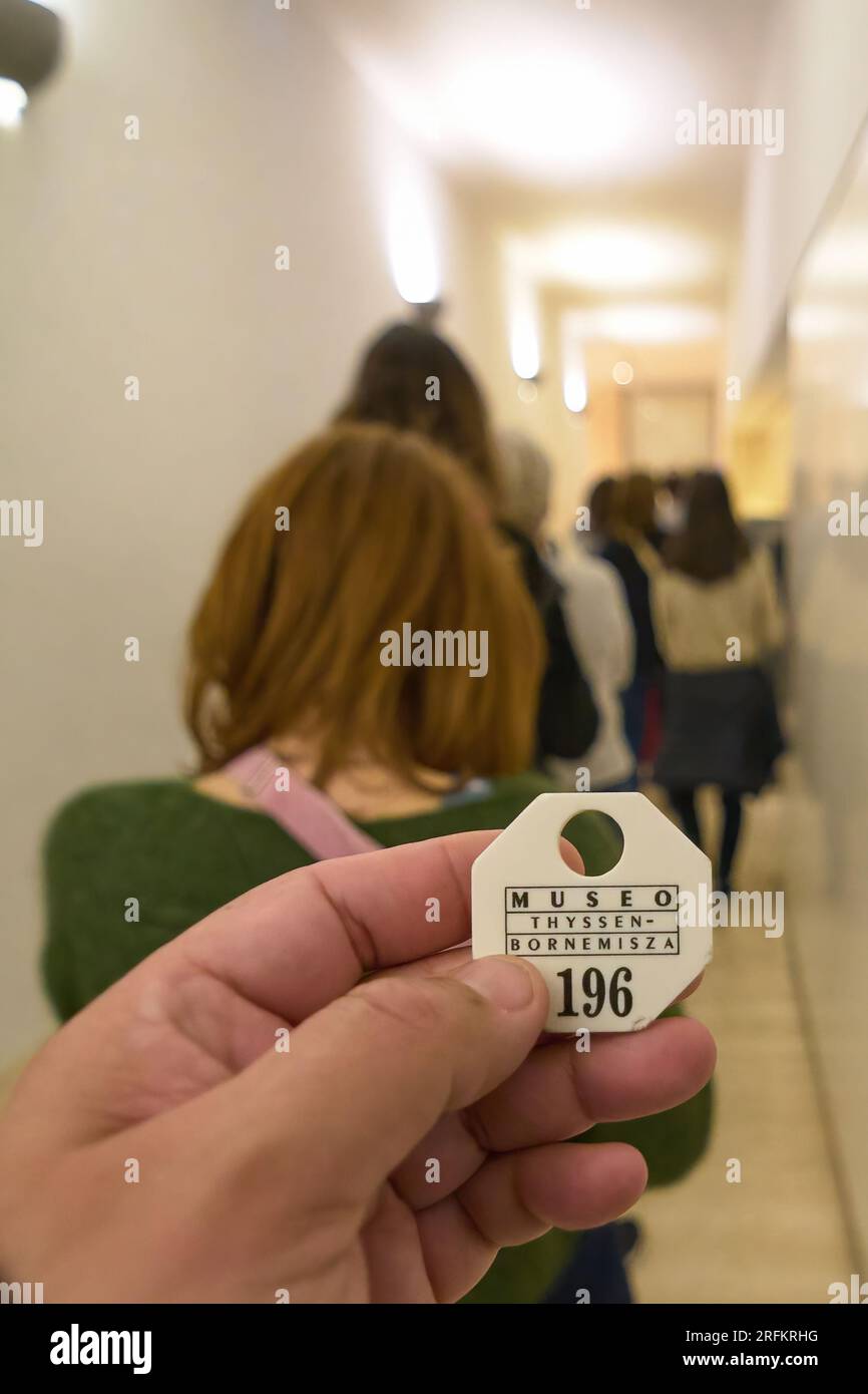 Hand holding cloakroom token and unrecognizable group of people with ...