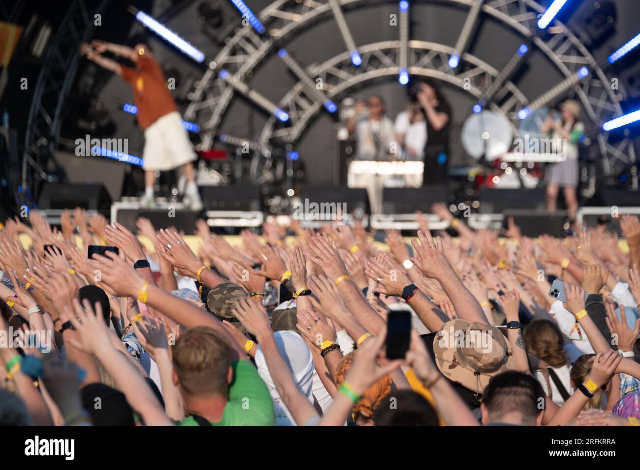 Back view of raised arms of many fans waving arms while dancing ...