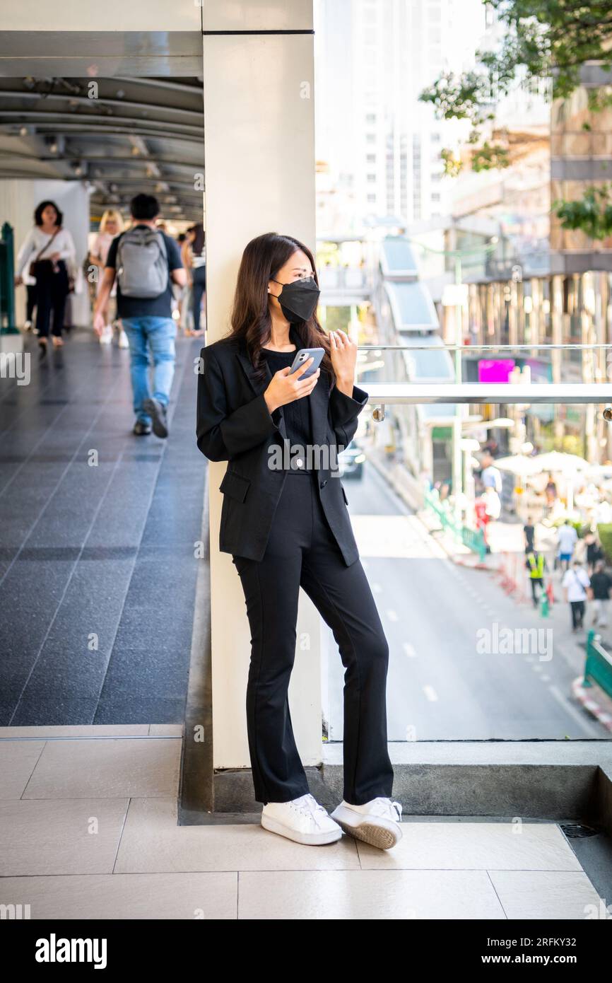 A young Thai girl takes a moment to check her phone at Chong Nonsi BTS ...