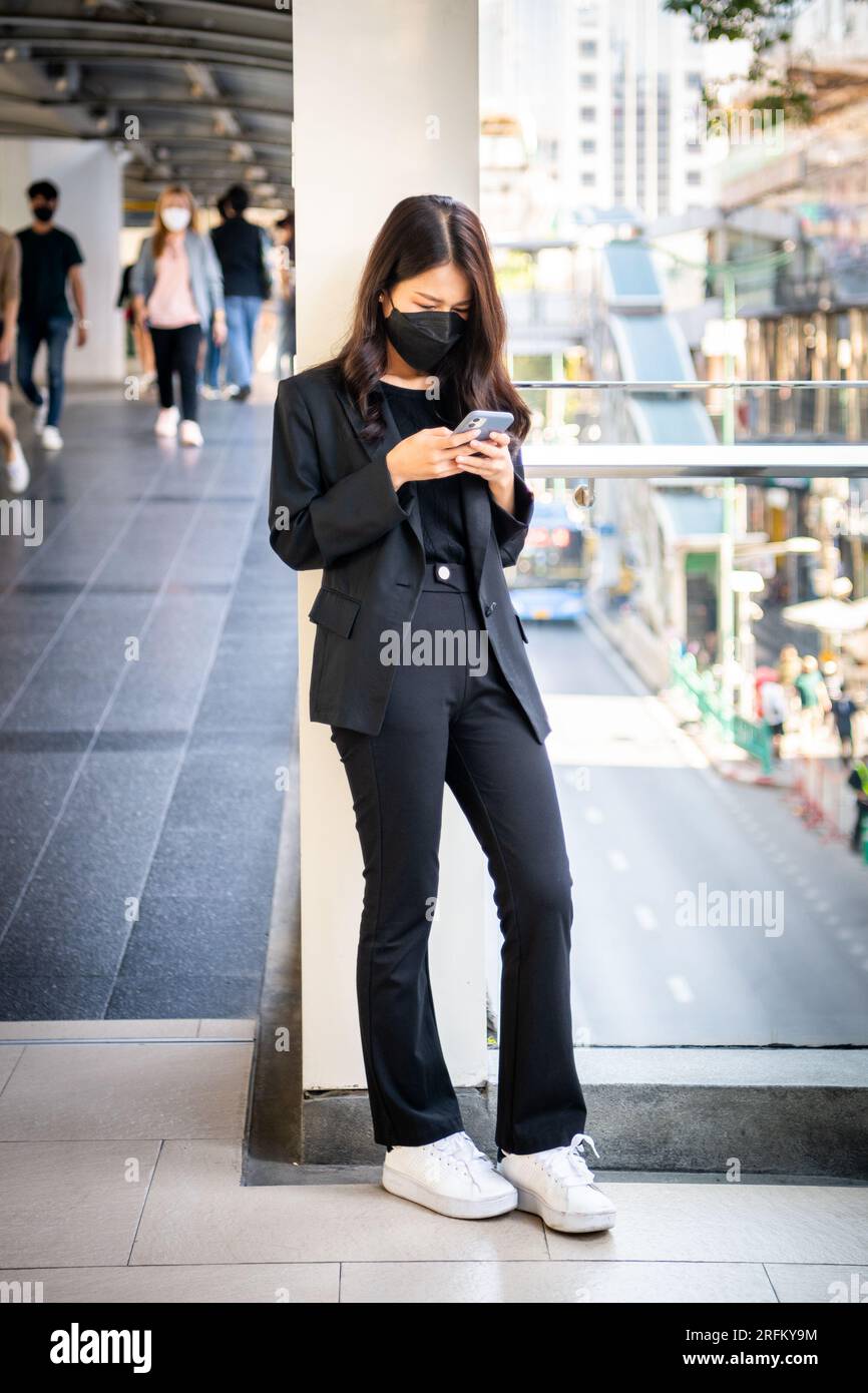 A young Thai girl takes a moment to check her phone at Chong Nonsi BTS ...