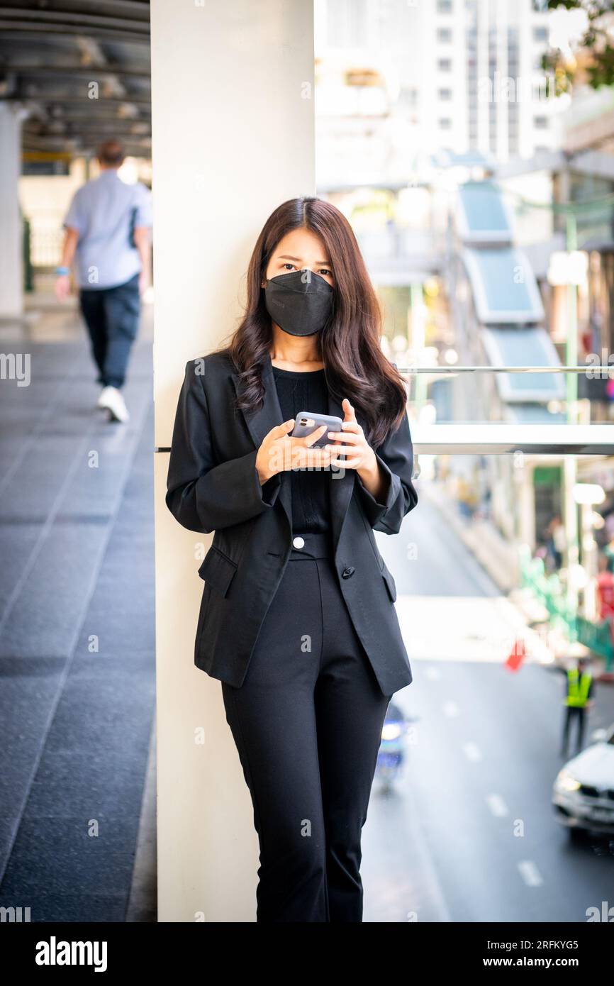A young Thai girl takes a moment to check her phone at Chong Nonsi BTS ...