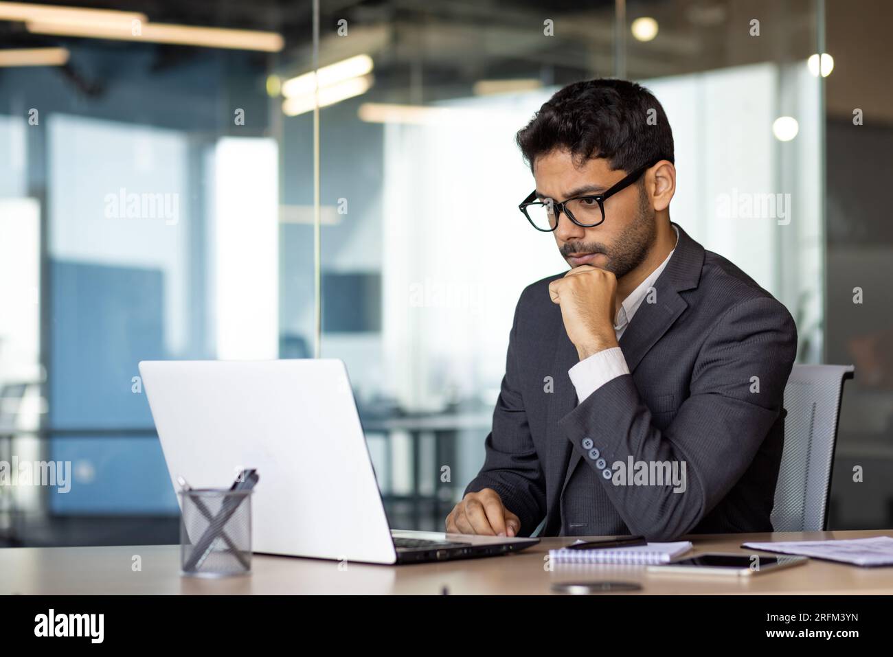 Young thinking businessman at workplace with laptop inside office, boss ...