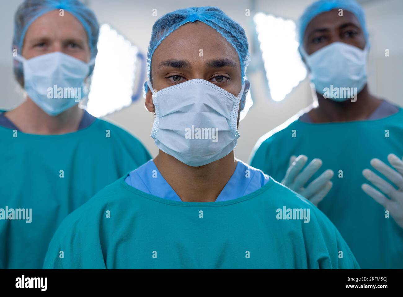 Portrait of diverse male surgeons wearing surgical gowns in operating ...
