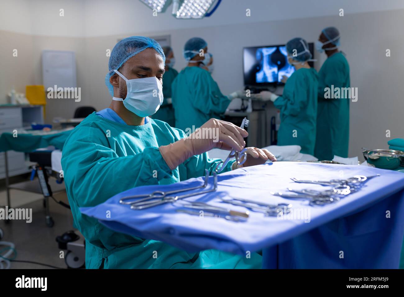 Diverse surgeons wearing surgical gowns operating on patient in ...