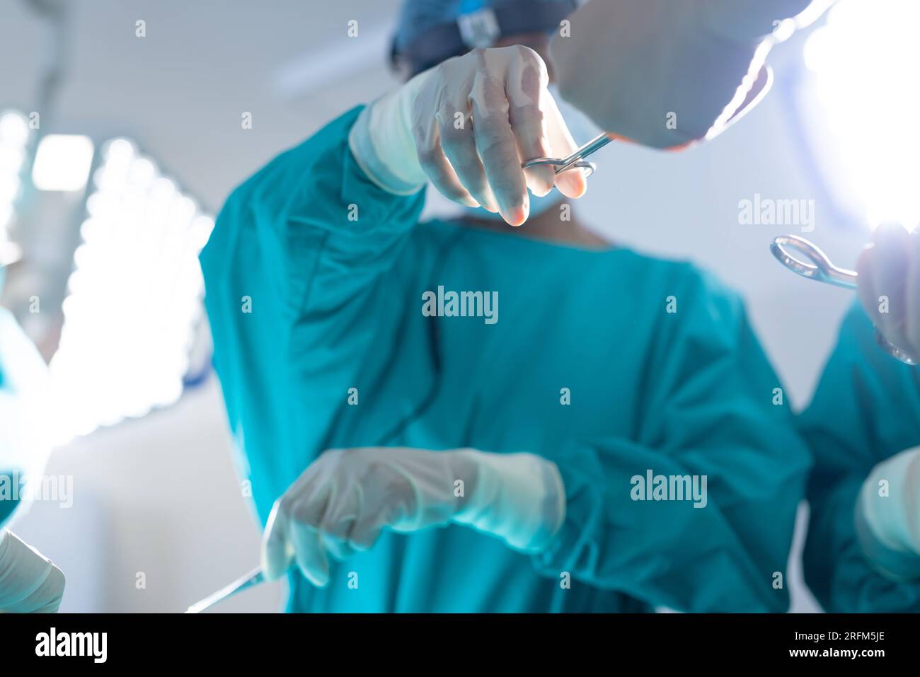 Diverse surgeons wearing surgical gowns operating on patient in ...