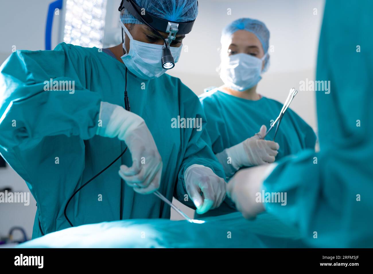 Diverse surgeons wearing surgical gowns operating on patient in ...