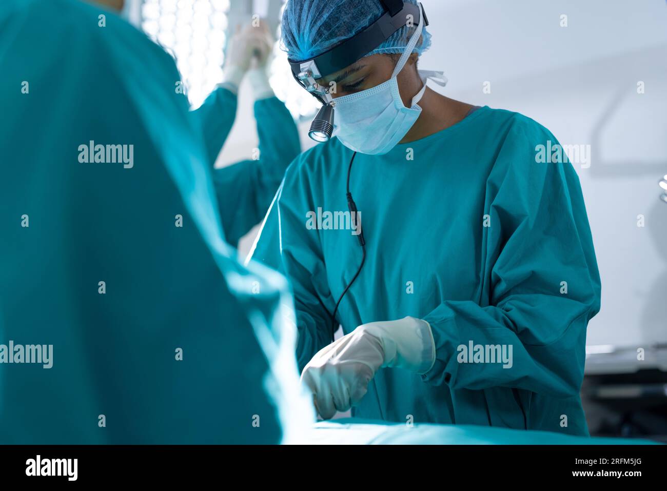 Diverse surgeons wearing surgical gowns operating on patient in ...