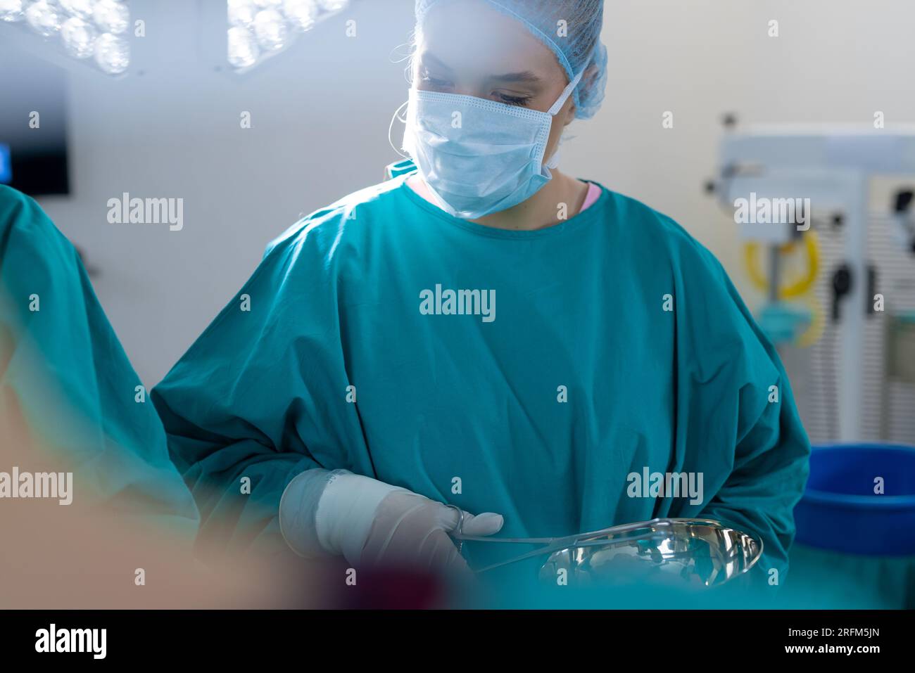 Diverse surgeons wearing surgical gowns operating on patient in ...