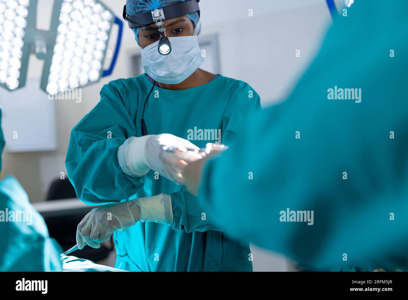Diverse surgeons wearing surgical gowns operating on patient in ...