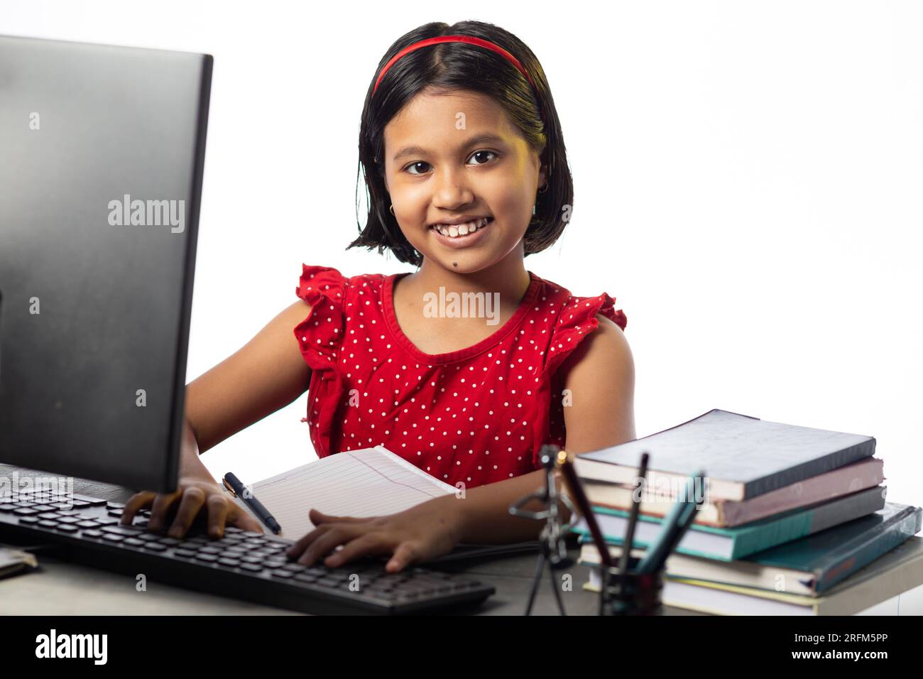 A pretty beautiful Indian girl child studying with desktop computer at ...