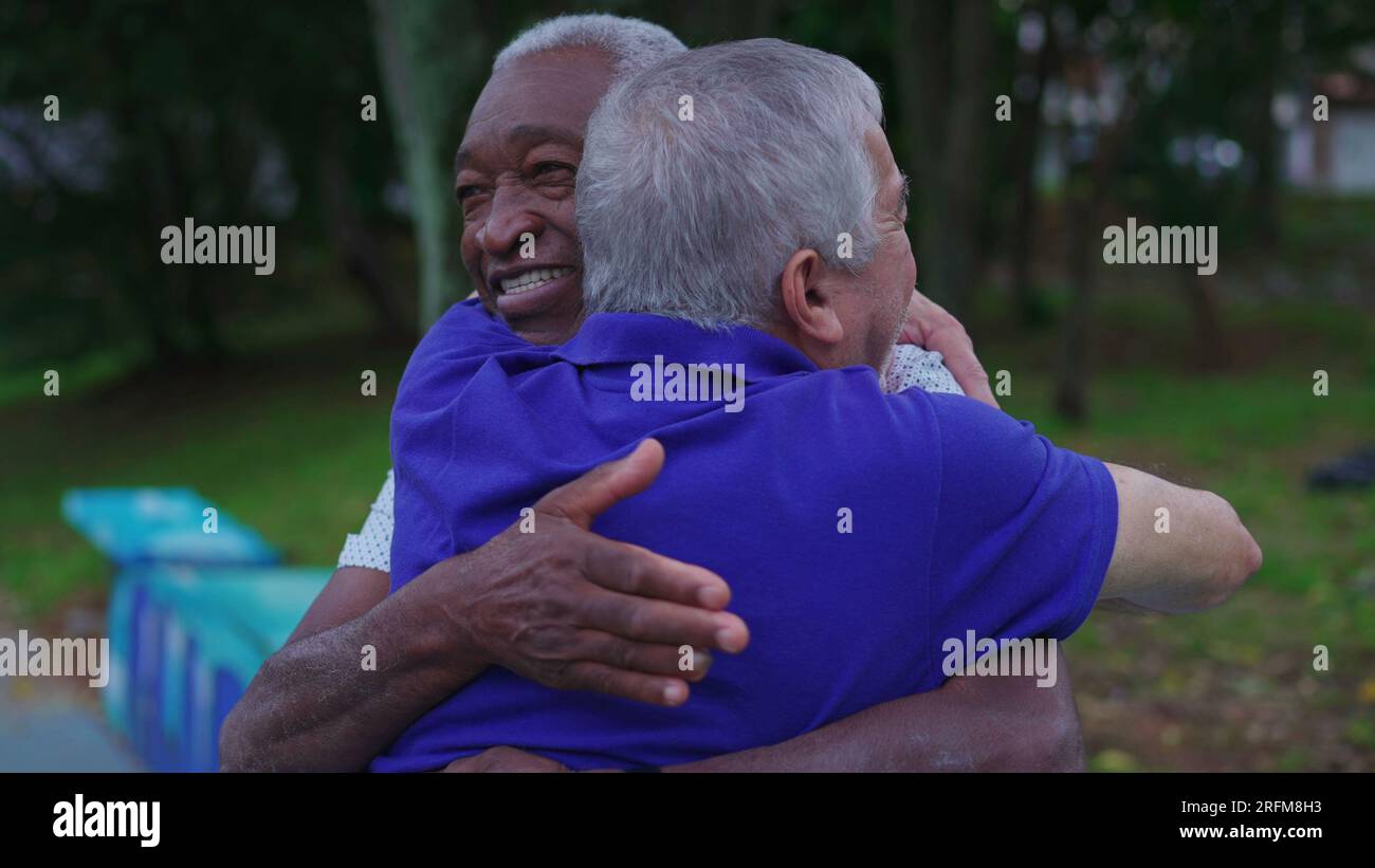 Two diverse friends hugging each other at park. An African American ...