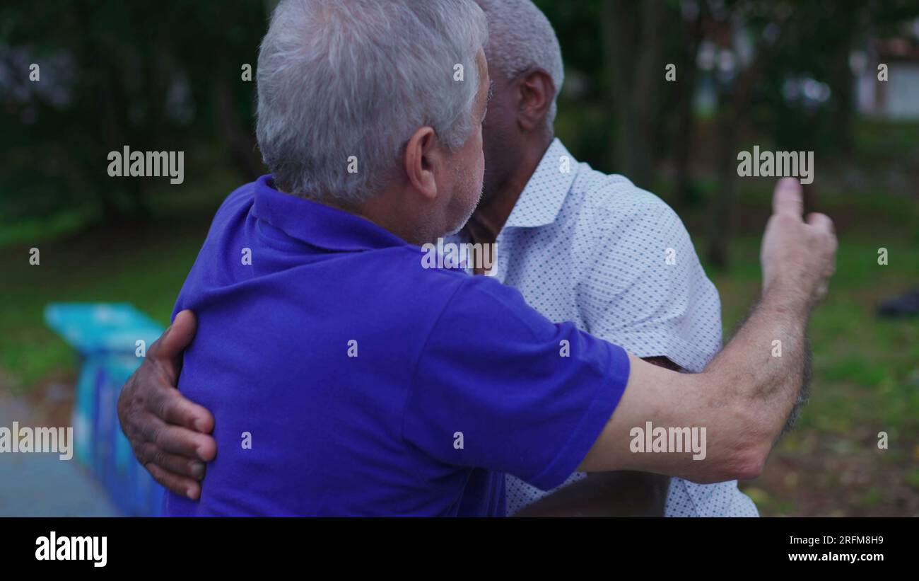 Two diverse friends hugging each other at park. An African American ...