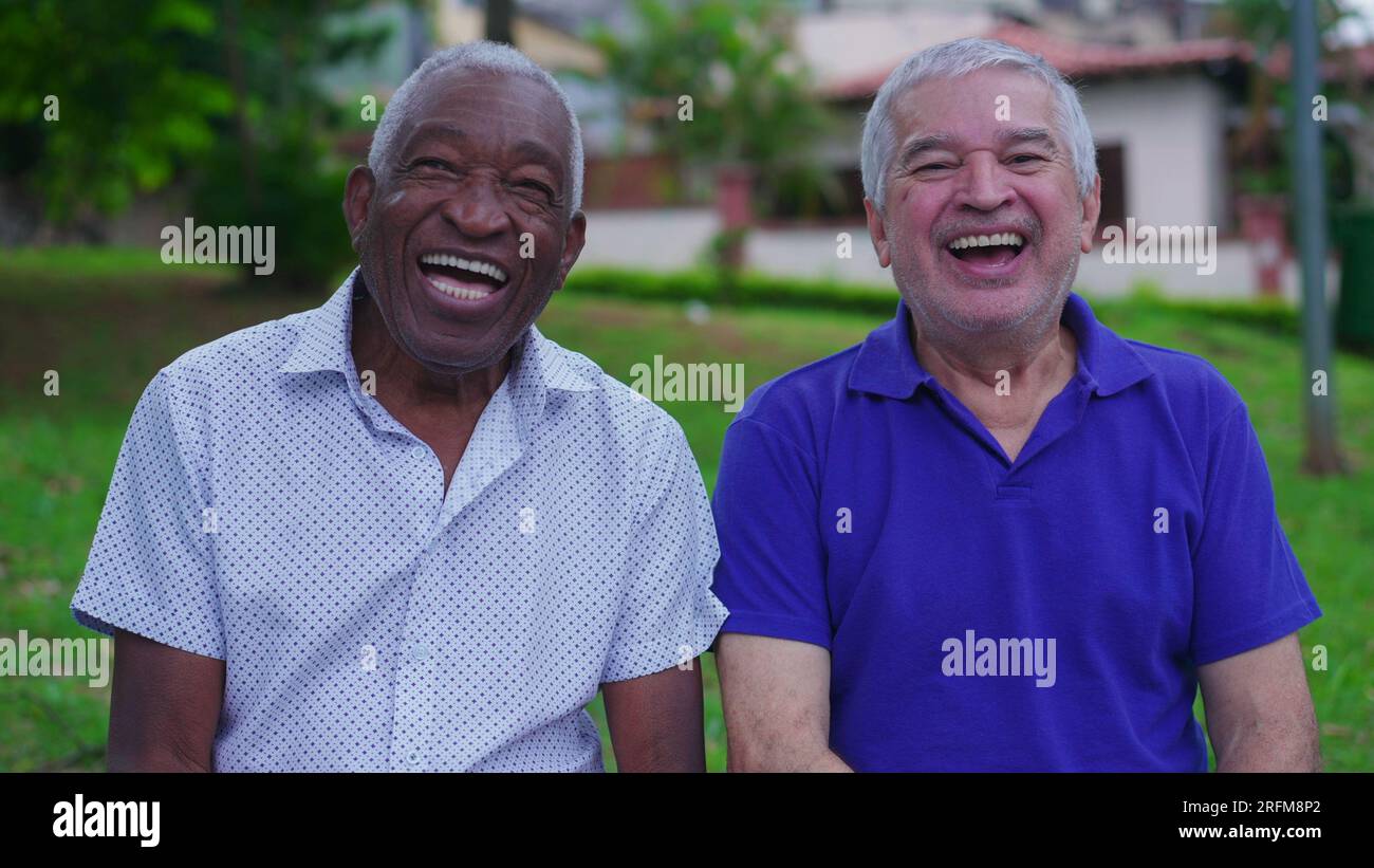 Two joyful Diverse senior friends laughing and smiling together on park ...
