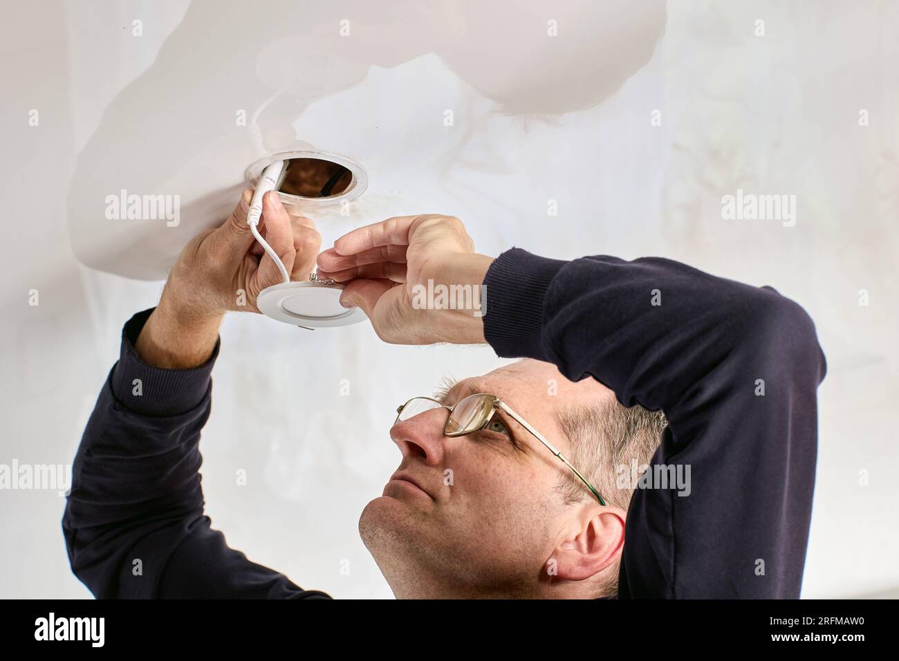 Spotlight in stretch suspended ceiling is installed in socket after ...