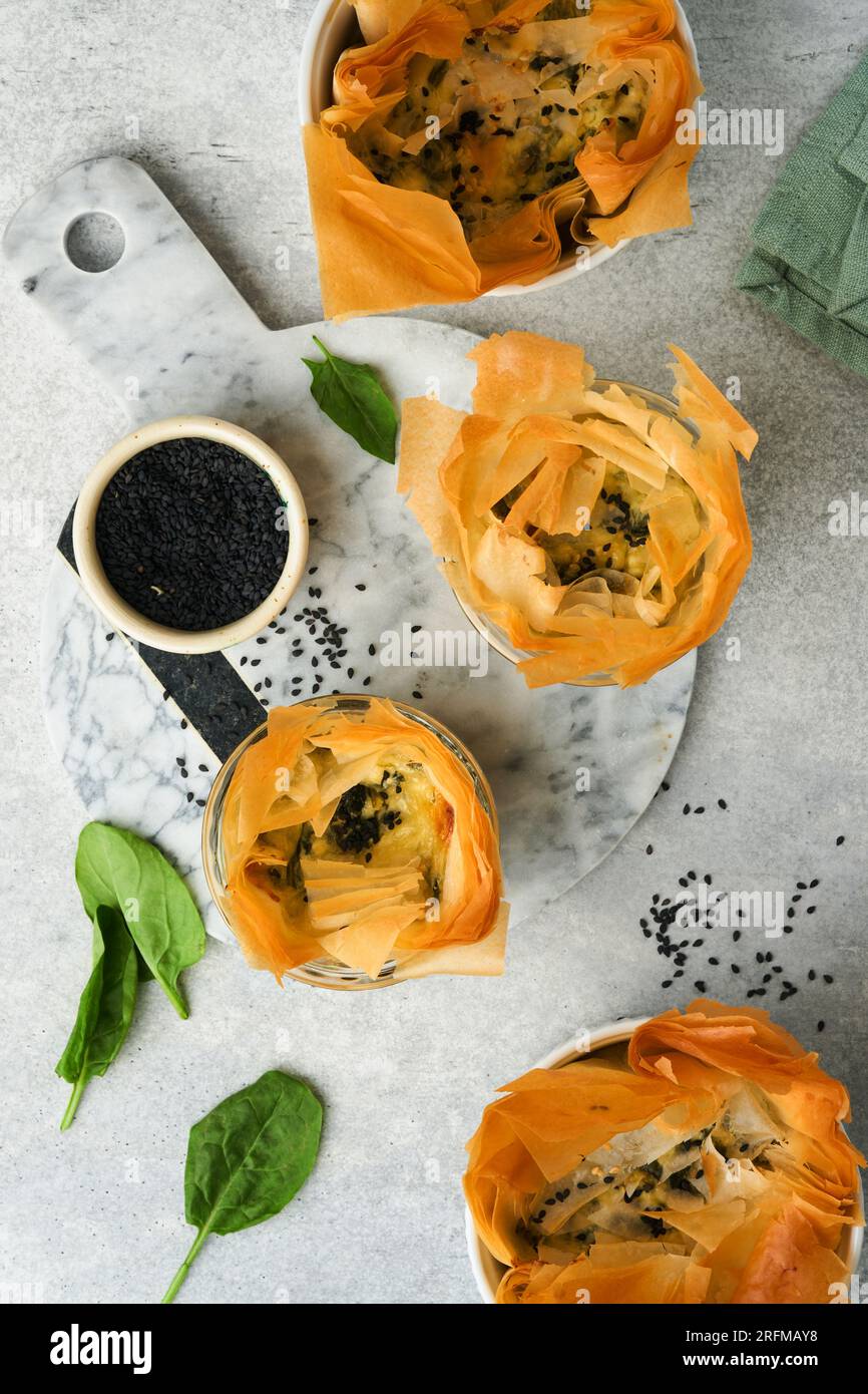 Filo pies with soft feta cheese and spinach in ceramic molds on old ...