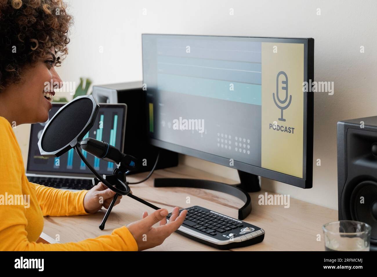 Latin woman recording podcast with microphone and computer inside home ...