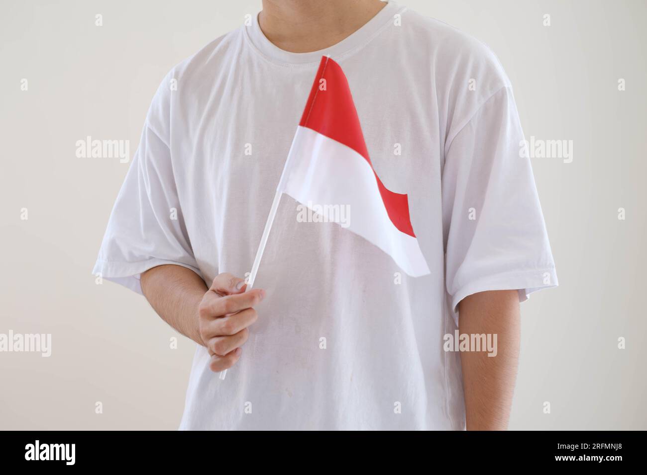A man wearing white T-Shirt is holding Bendera Indonesia or Indonesian ...