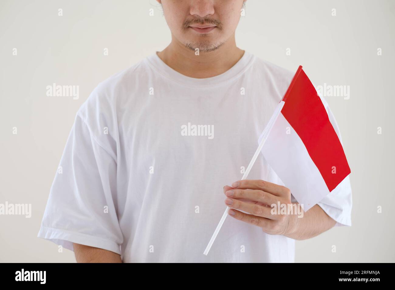 A man wearing white T-Shirt is holding Bendera Indonesia or Indonesian ...