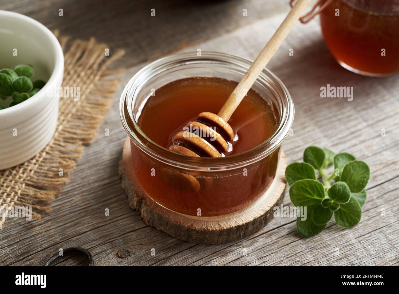 A jar of Plectranthus amboinicus syrup with a honey dipper and fresh ...