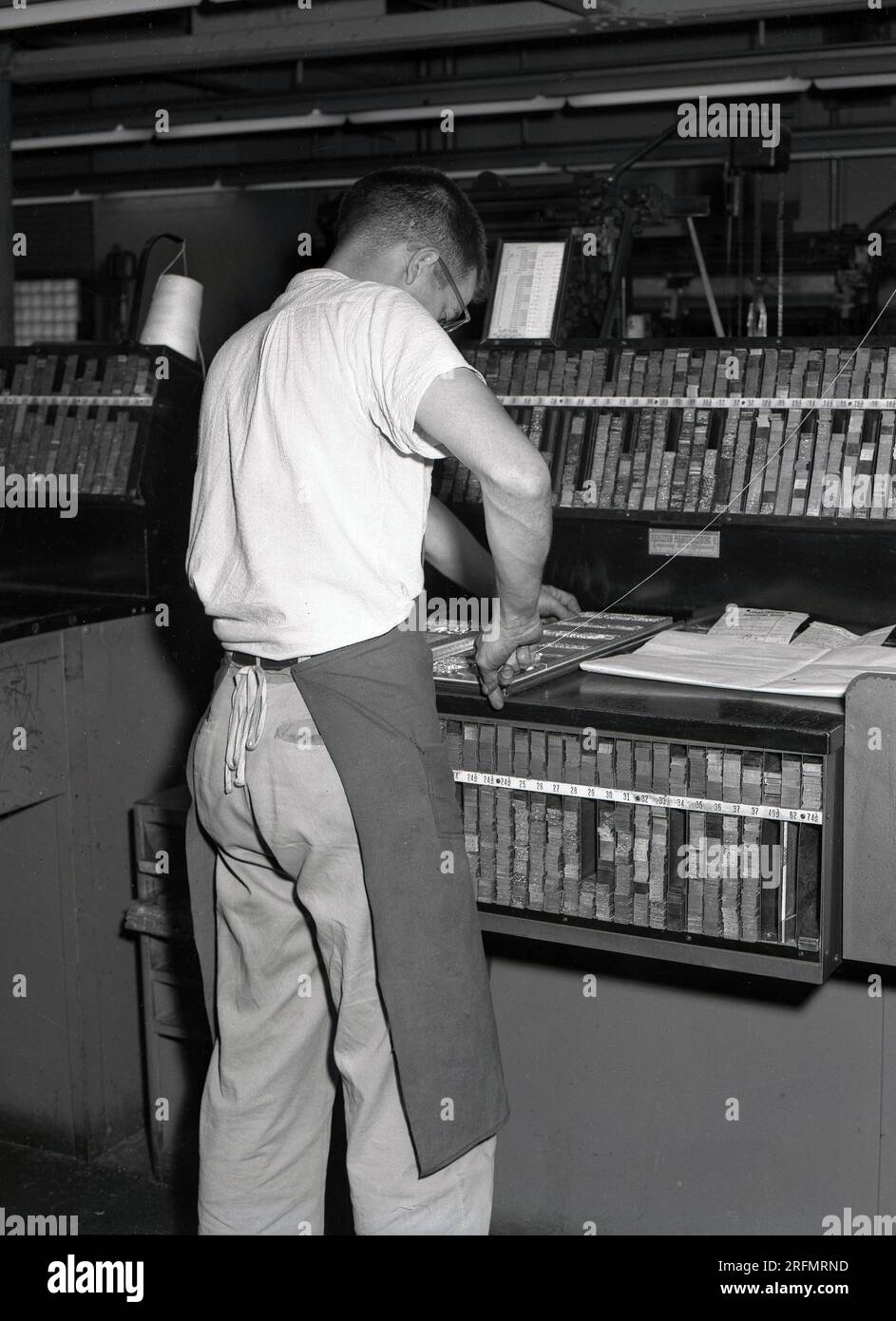 1950s, historical, male worker wearing a canvas work apron at a letter ...