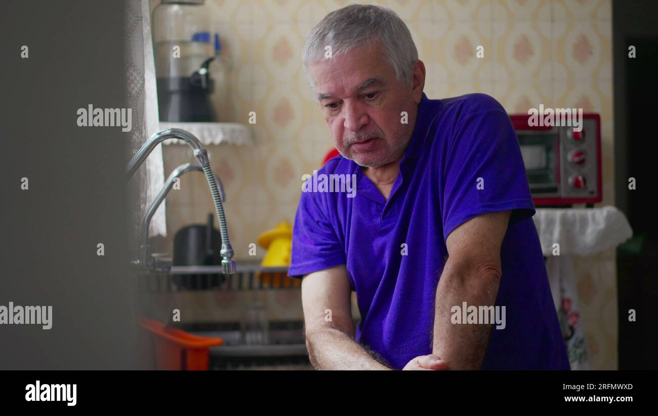 Worried senior man leaning on kitchen sink suffering from mental ...