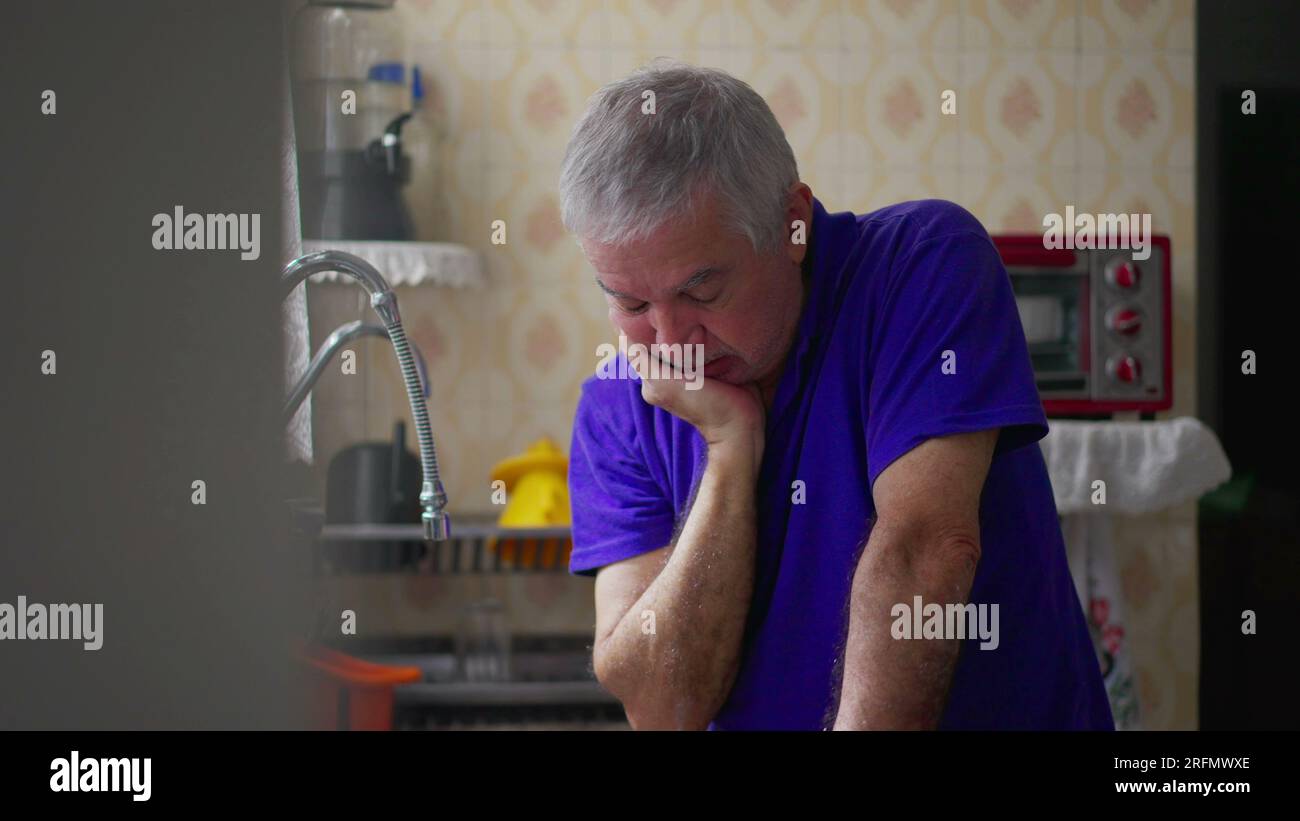 Worried senior man leaning on kitchen sink suffering from mental ...