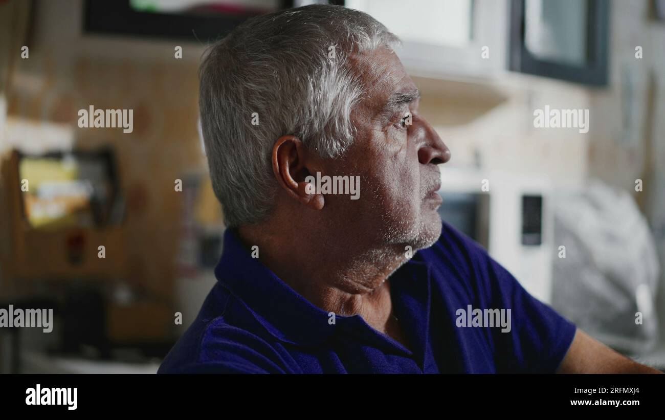 Sad depressed unshaven senior lost in thought at home staring out home ...
