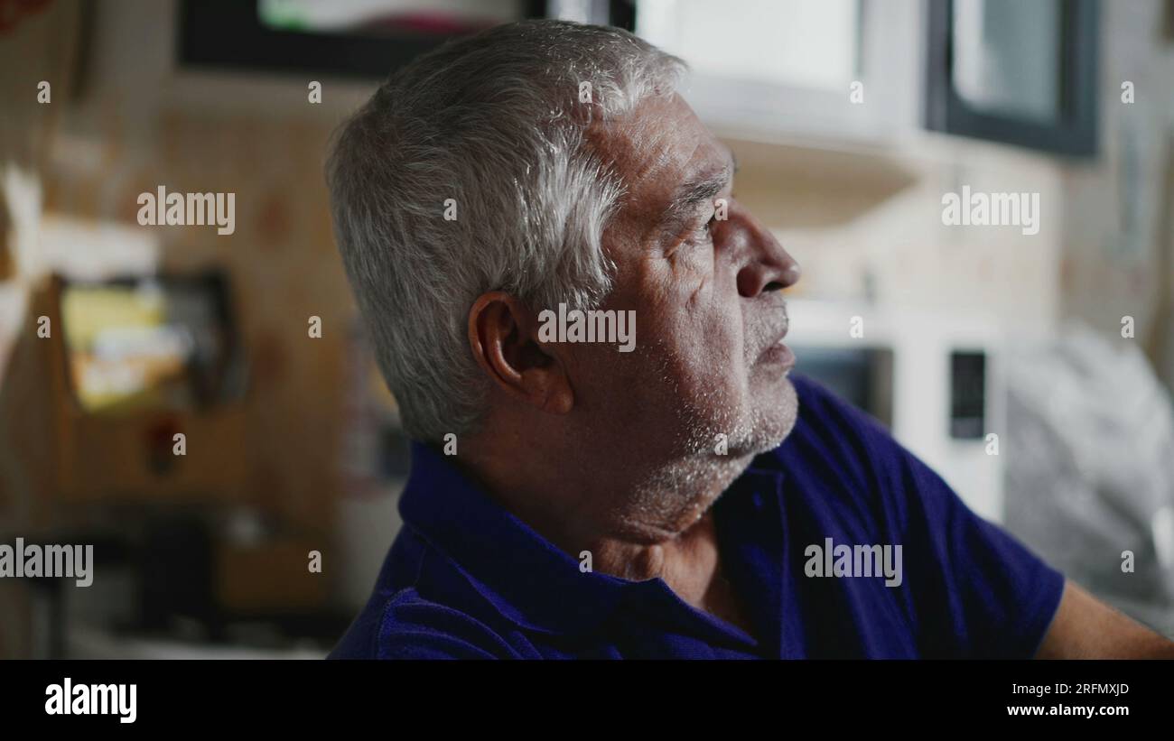 Sad depressed unshaven senior lost in thought at home staring out home ...