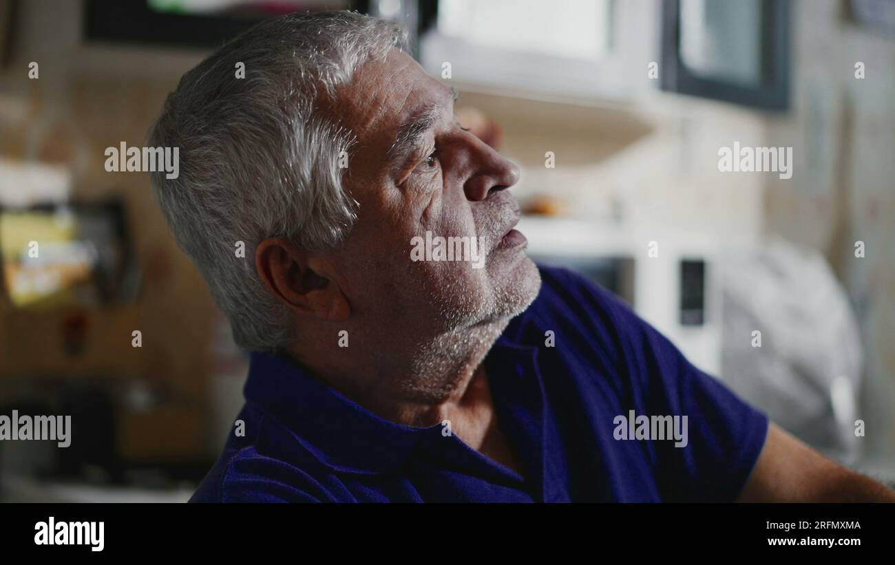 Sad depressed unshaven senior lost in thought at home staring out home ...