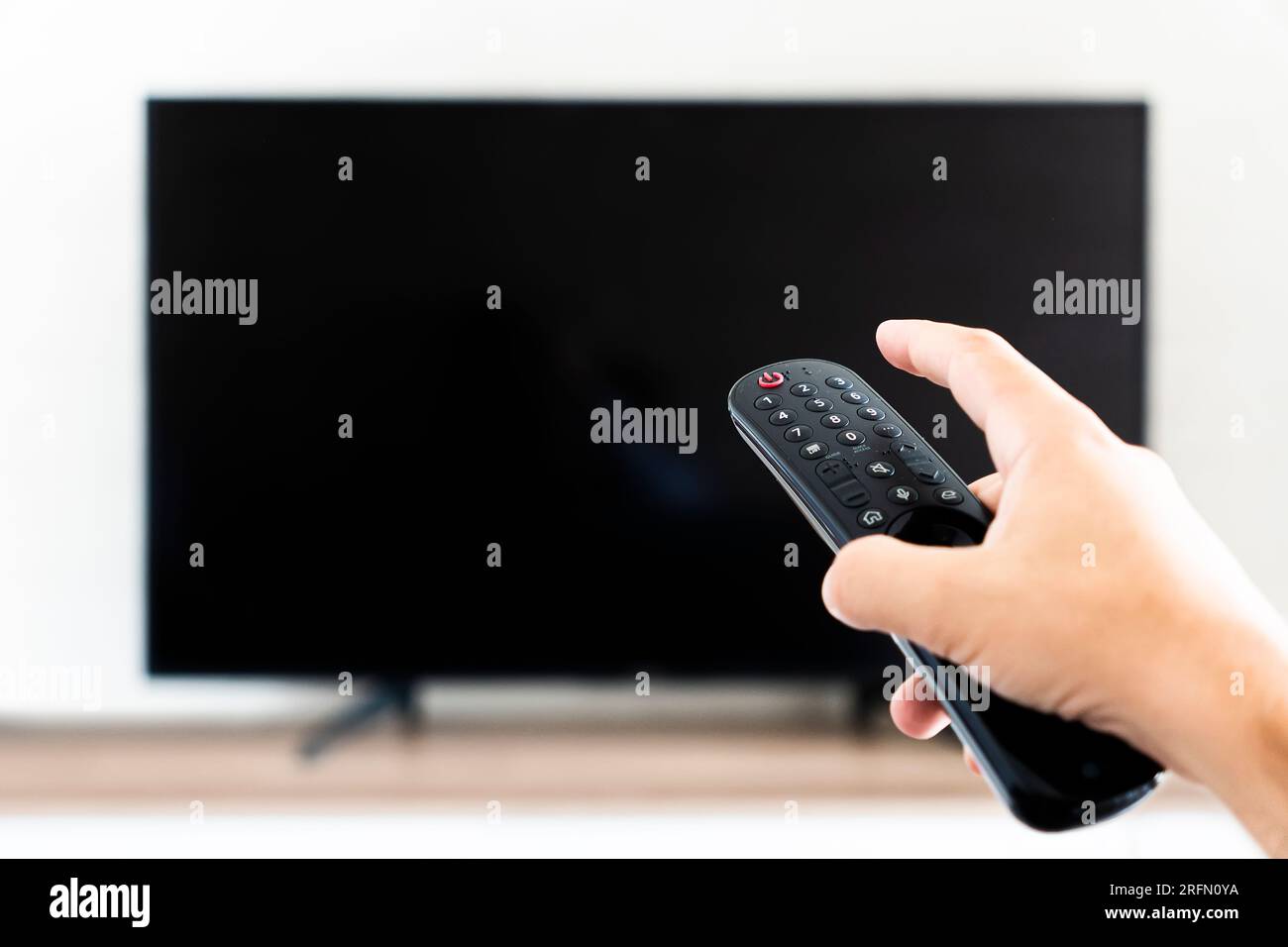 Hand holding remote control for turn off TV. an empty black TV screen ...
