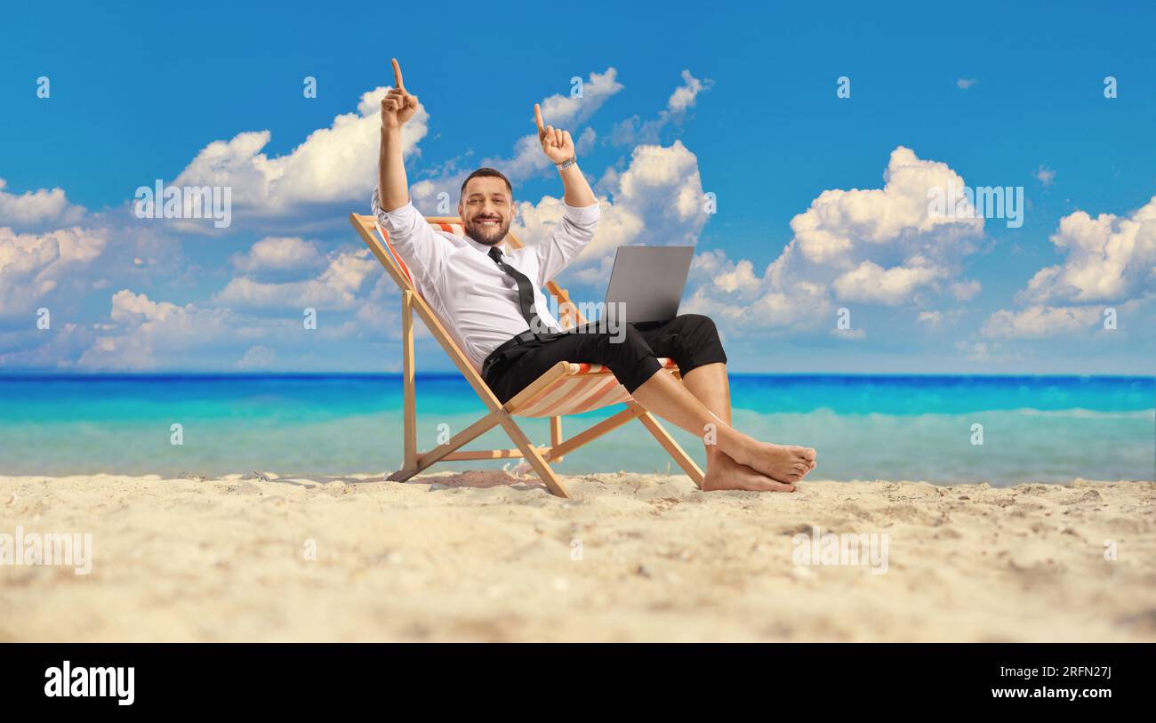 Happy businessman at the beach with a laptop computer sitting by the ...