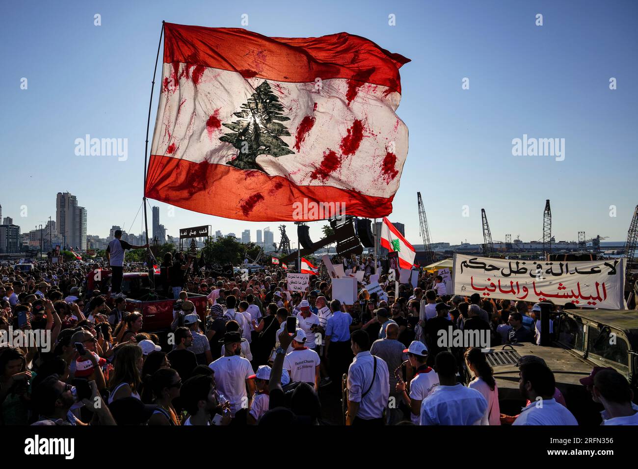 People wave a huge Lebanese national flag as gather outside the port to ...