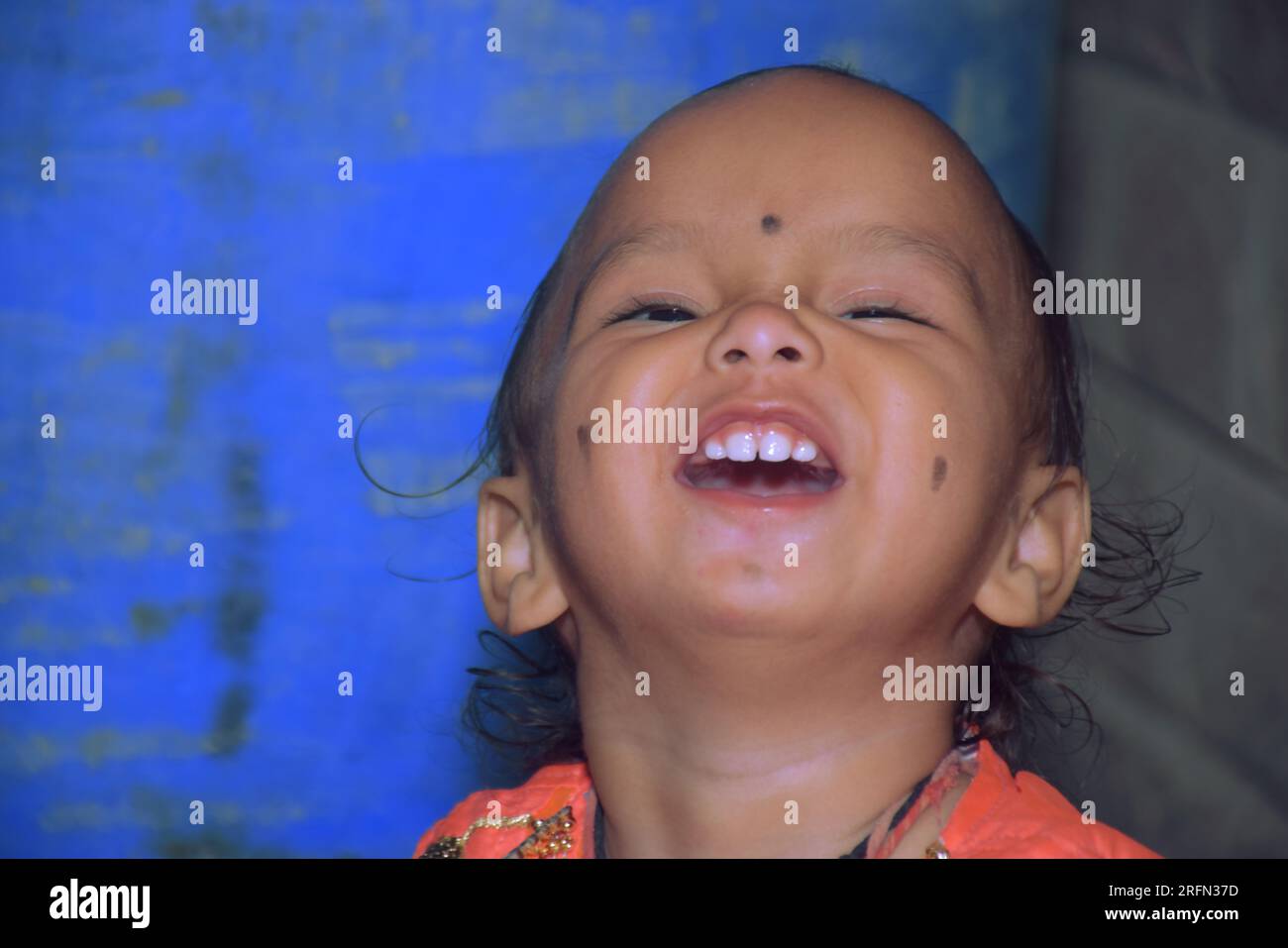cute baby girl making smiley face, with blue background Stock Photo - Alamy
