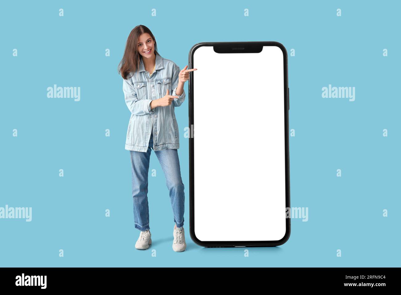 Trendy young woman in stylish jeans clothes and with big mobile phone ...