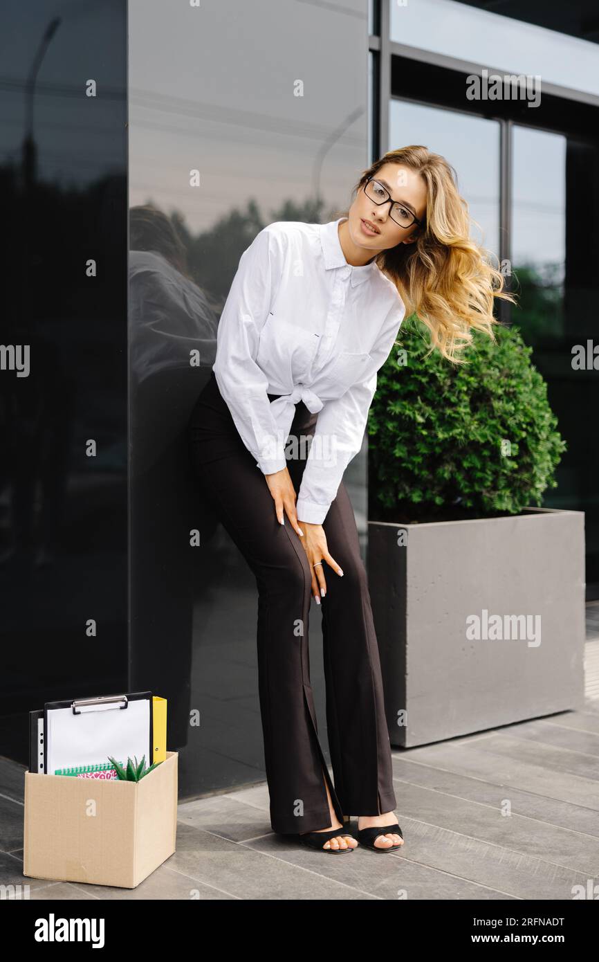 Caucasian businesswoman standing outdoors next to the box of stuff ...