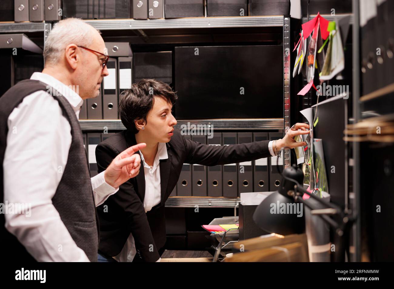 Investigators analyzing board with crime scene evidence, working late ...