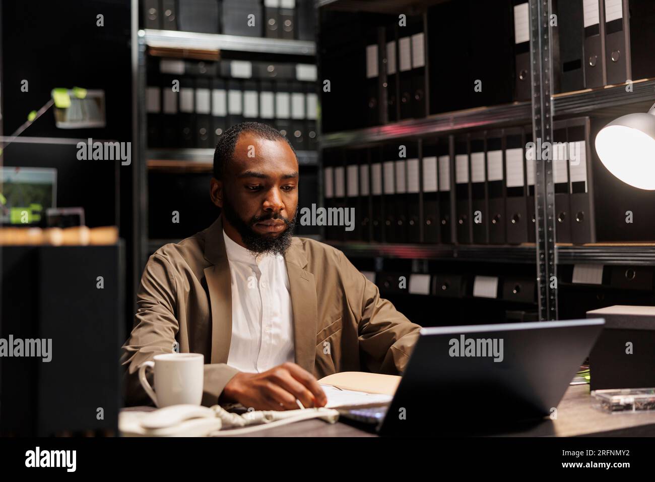 African american cop working overtime on laptop in dark detective ...