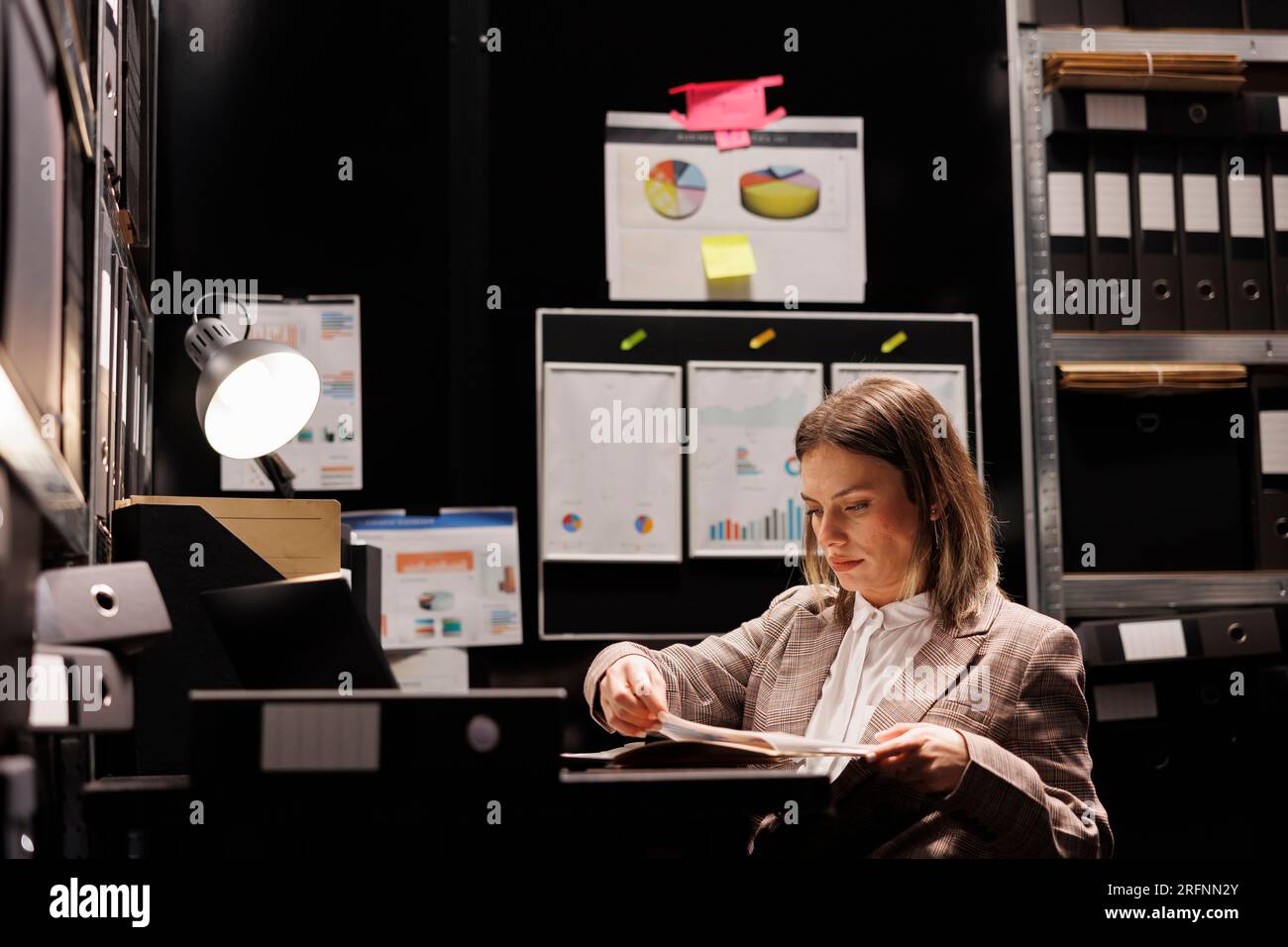 Bookkeeper reading management report in arhive room, working late at ...