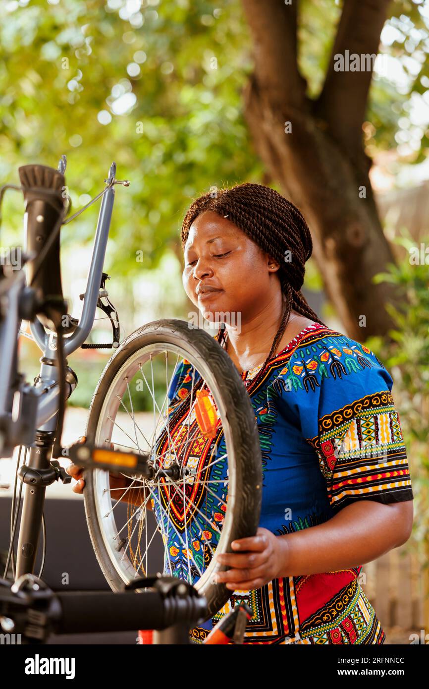 Focused active young female cyclist ensures bike is well-prepared for ...
